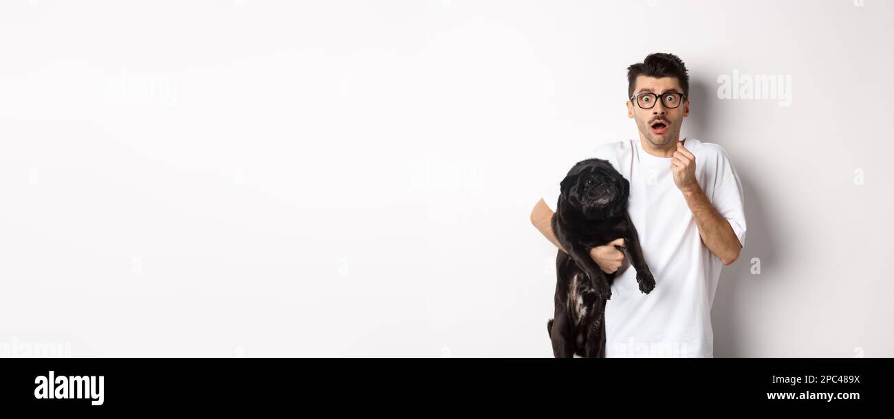 Scared hipster hugging his cute black puppy and staring at camera ...
