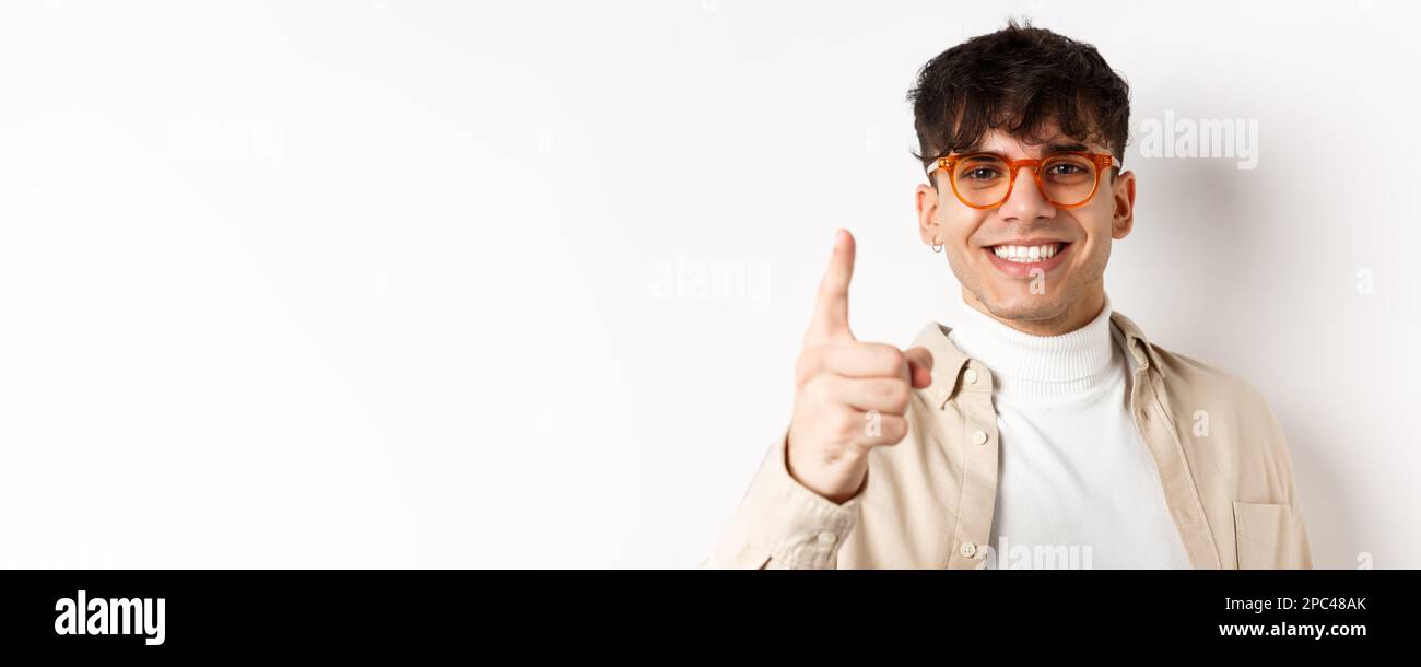 Close-up of lucky handsome man in glasses, smiling and pointing finger ...