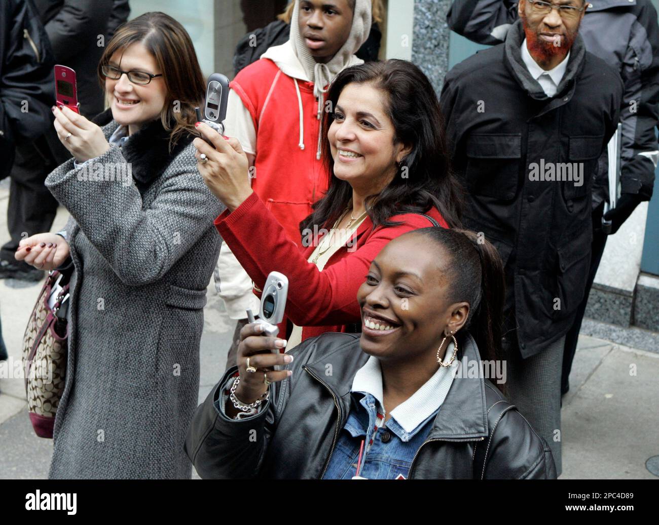 Members of the public stand on a sidewalk to look and photograph the ...