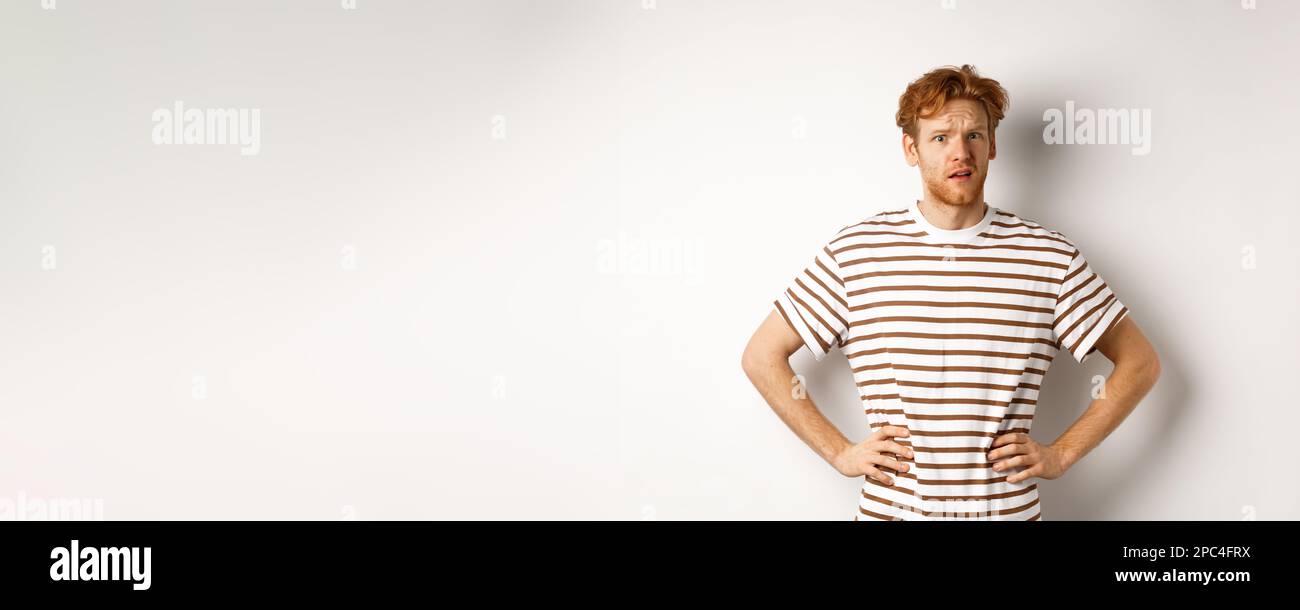 Confused and offended man with ginger curly hair staring at camera ...