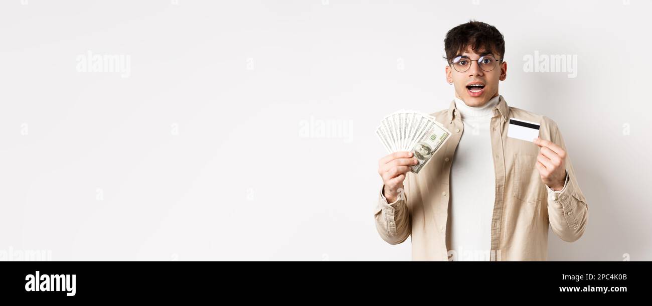 Excited young guy showing dollar bills and credit card, earn money and ...