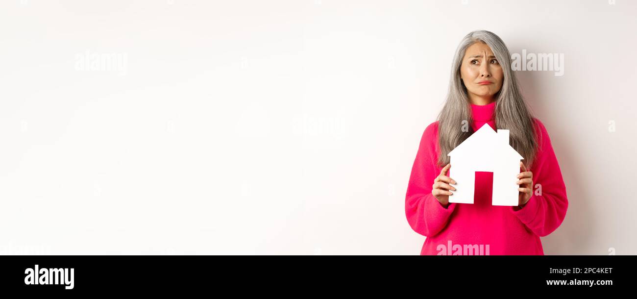 Real estate. Sad asian senior woman dreaming about own property ...