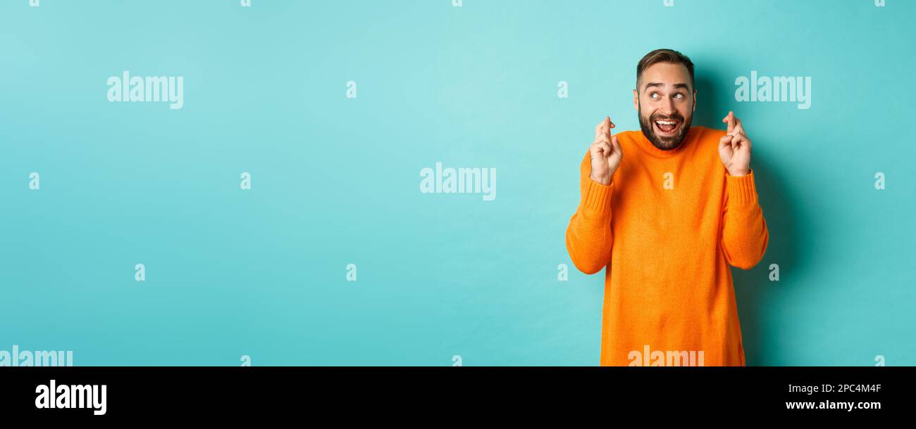 Excited man expecting something with anticipation, hold fingers crossed ...