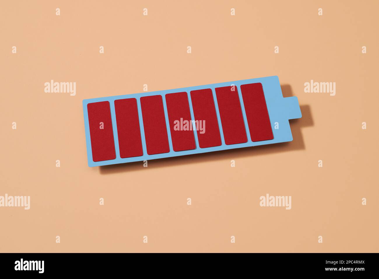 a cardboard depiction of a fully charged battery on a pale pink ...