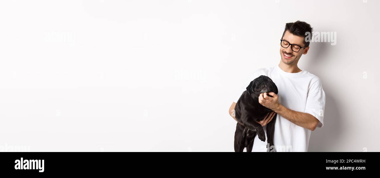 Happy dog owner scratching cute black pug face and smiling, pet his ...