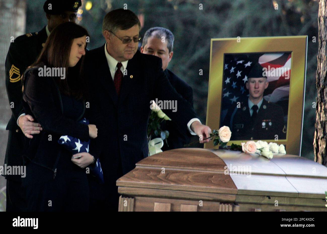 David Donica holds his daughter Courtney, left, as he places a flower ...