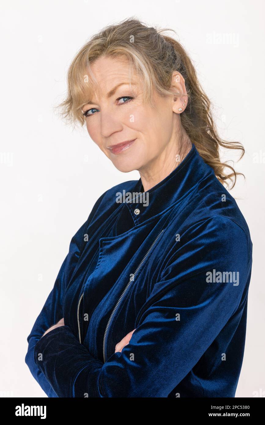 Attractive happy smiling female middle aged woman wearing a blue velvet jacket studio portrait ...