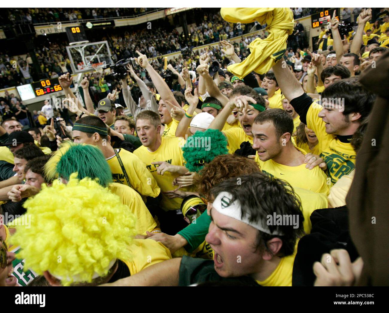 Oregon fans mob the floor as the scoreboard in the background shows the ...