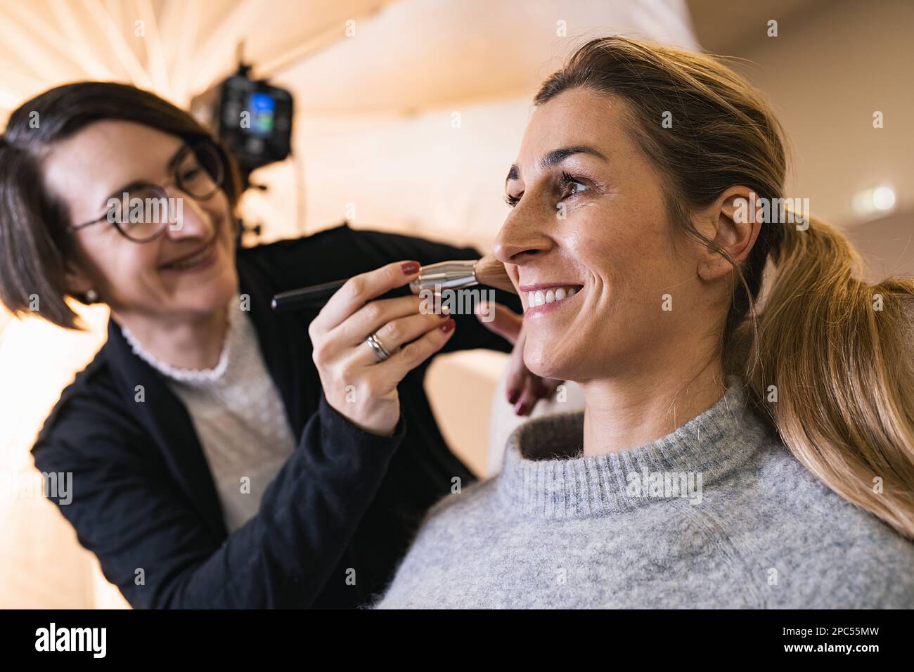 make up assistant applying make up with beauty brush to the face of a ...
