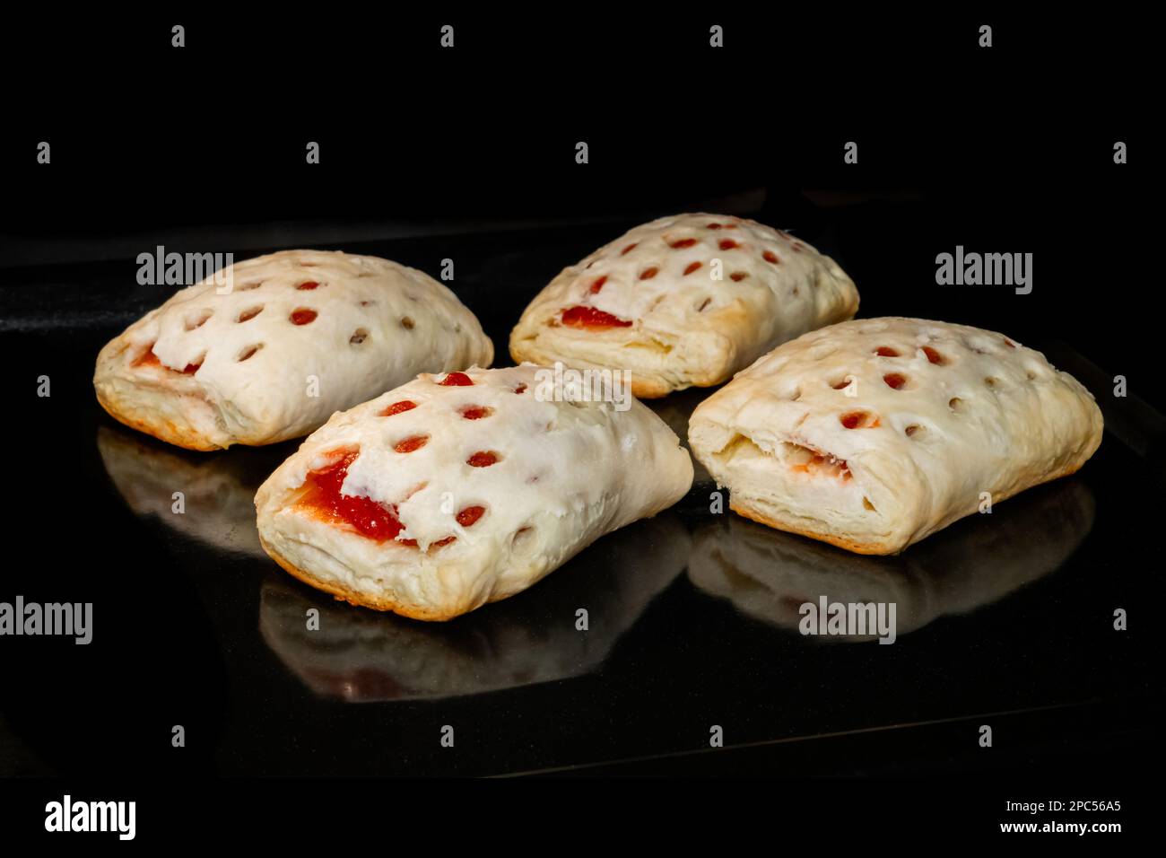 Four homemade buns with red strawberry jam baking in electric oven ...