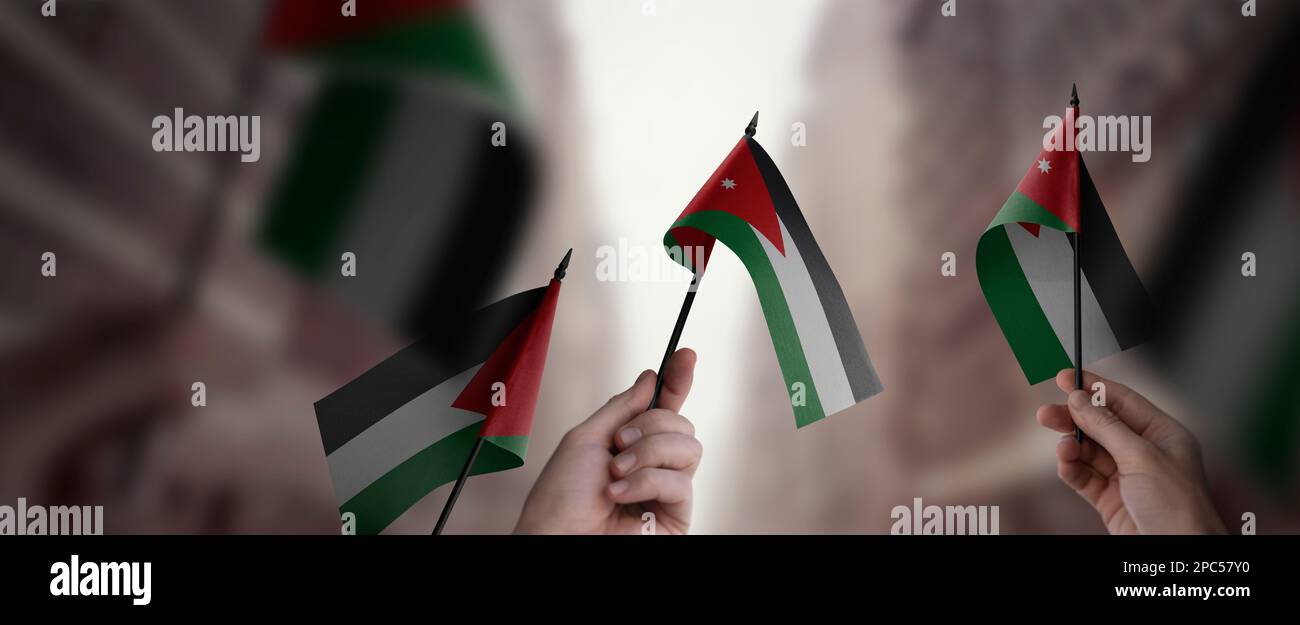 A group of people holding small flags of the Jordan in their hands ...
