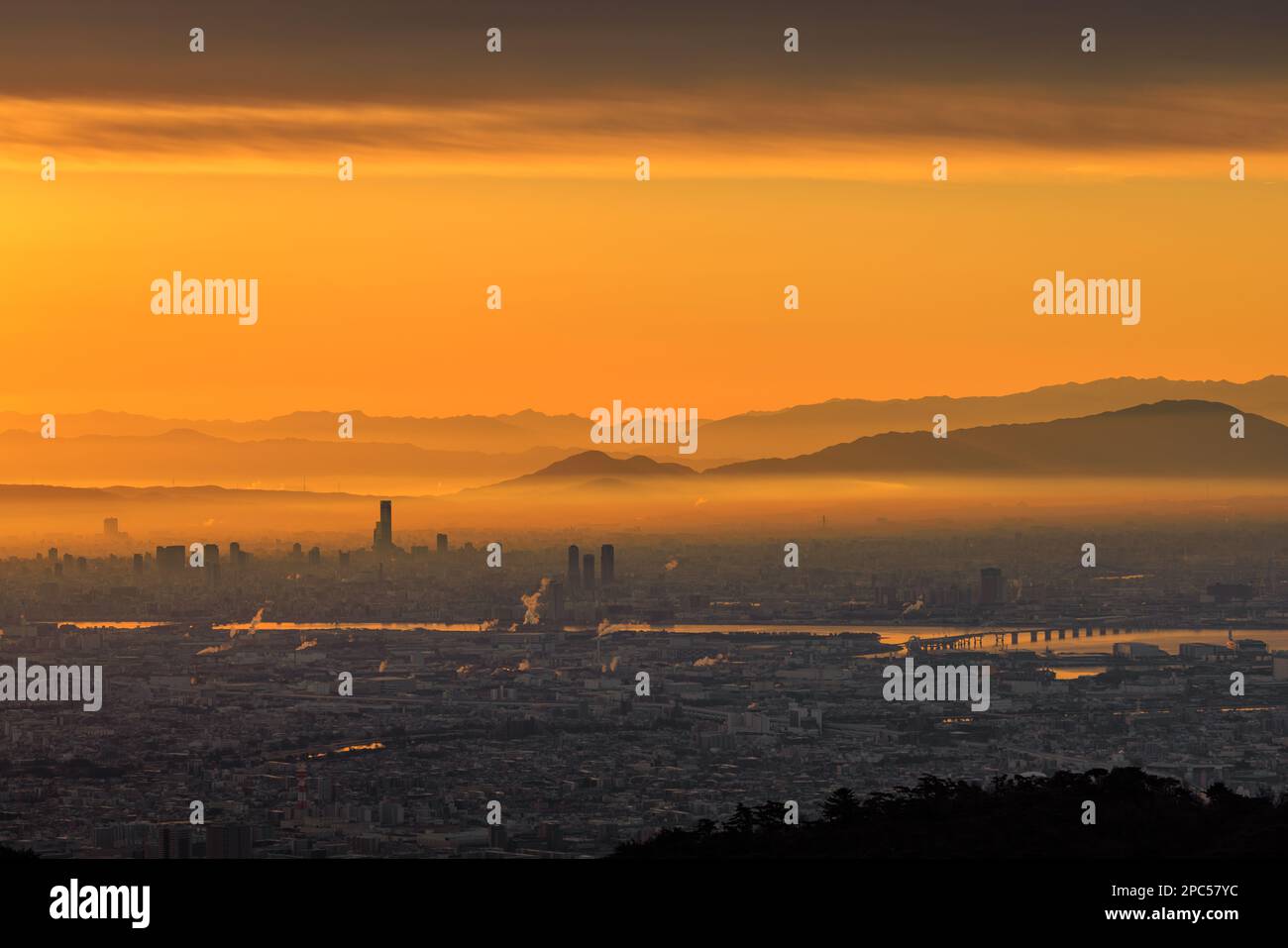 Orange sunrise glow between cloud and smog over sprawling city Stock ...