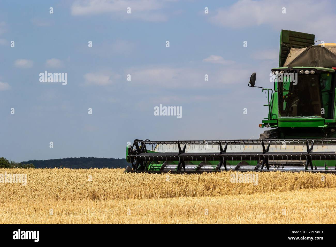Photo of combine harvester that is harvesting wheat with dust straw in ...
