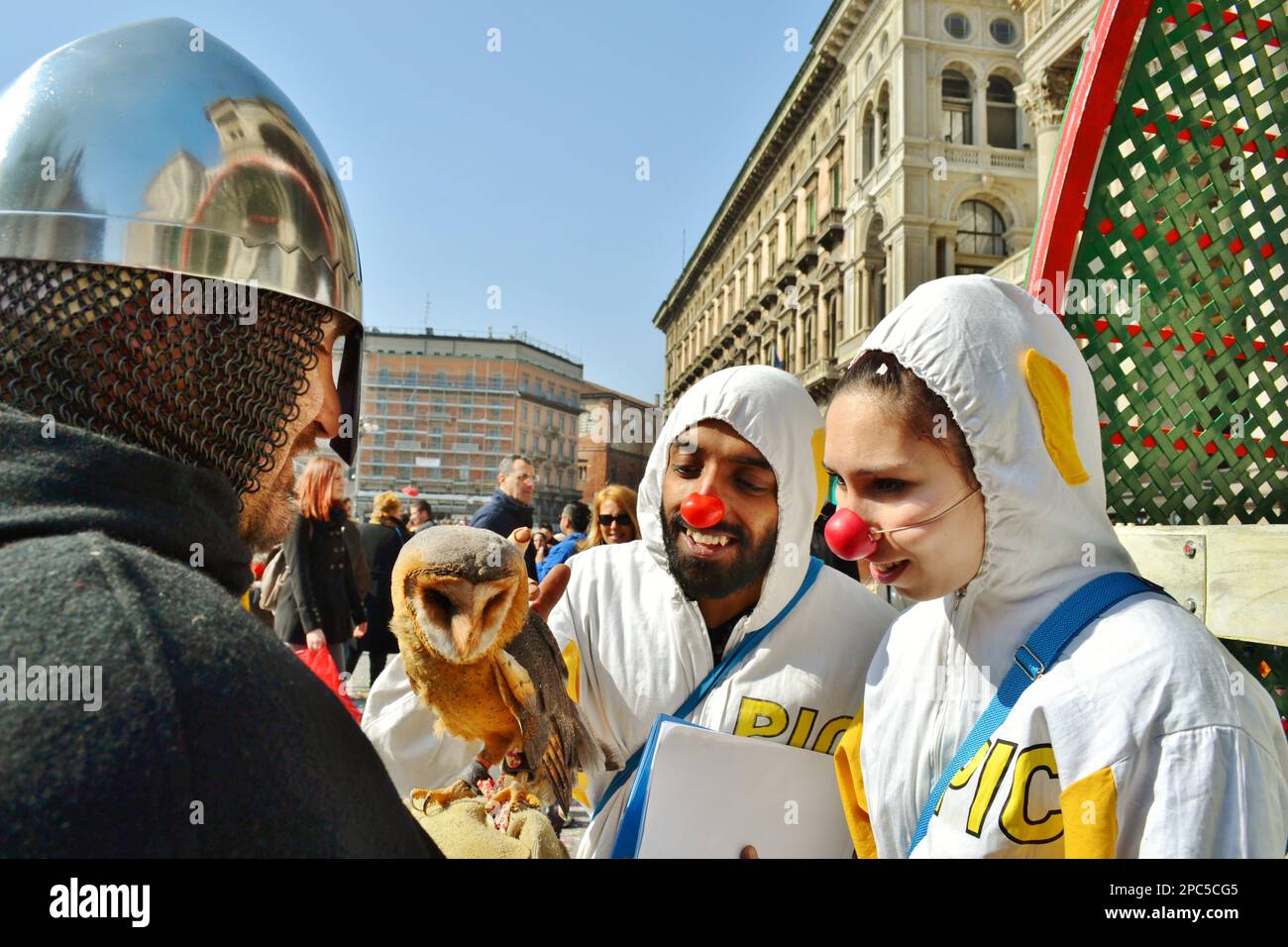 Two clowns in white costumes are watching a young brown owl sitting on ...