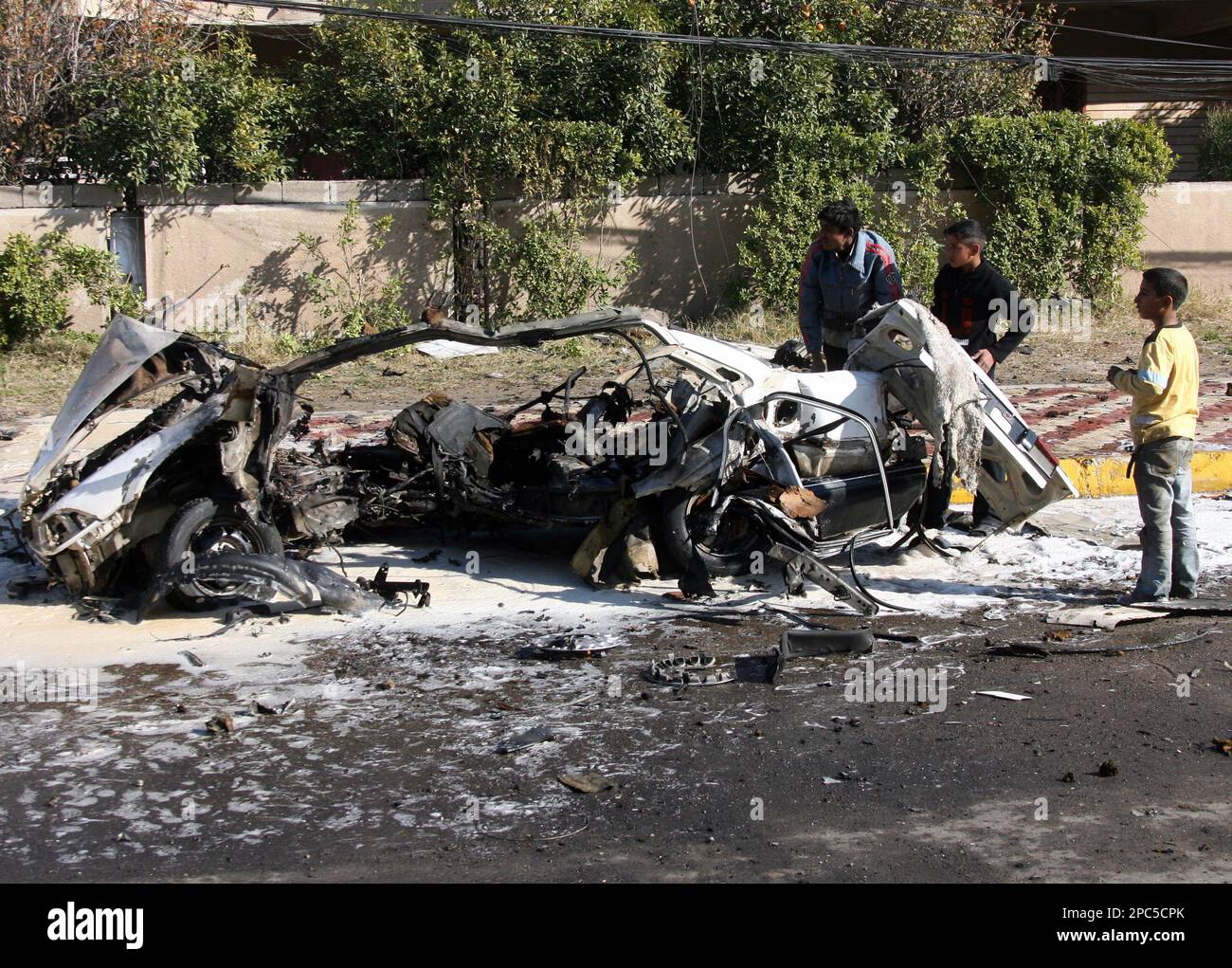 Iraqi children inspect a car that was destroyed in a car bomb explosion ...