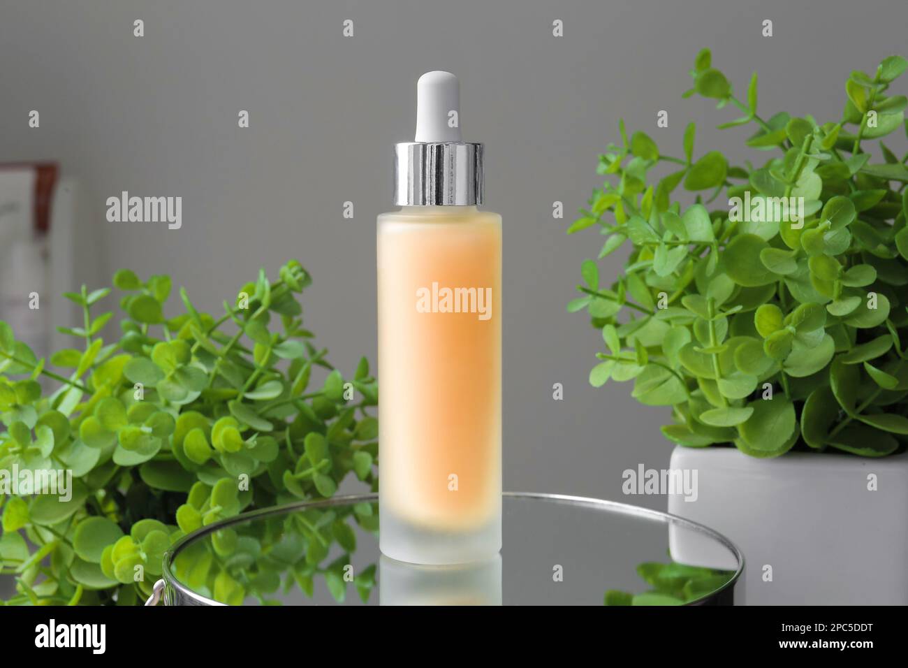 Cosmetics on a mirror surface. Serum for the face on a green background ...