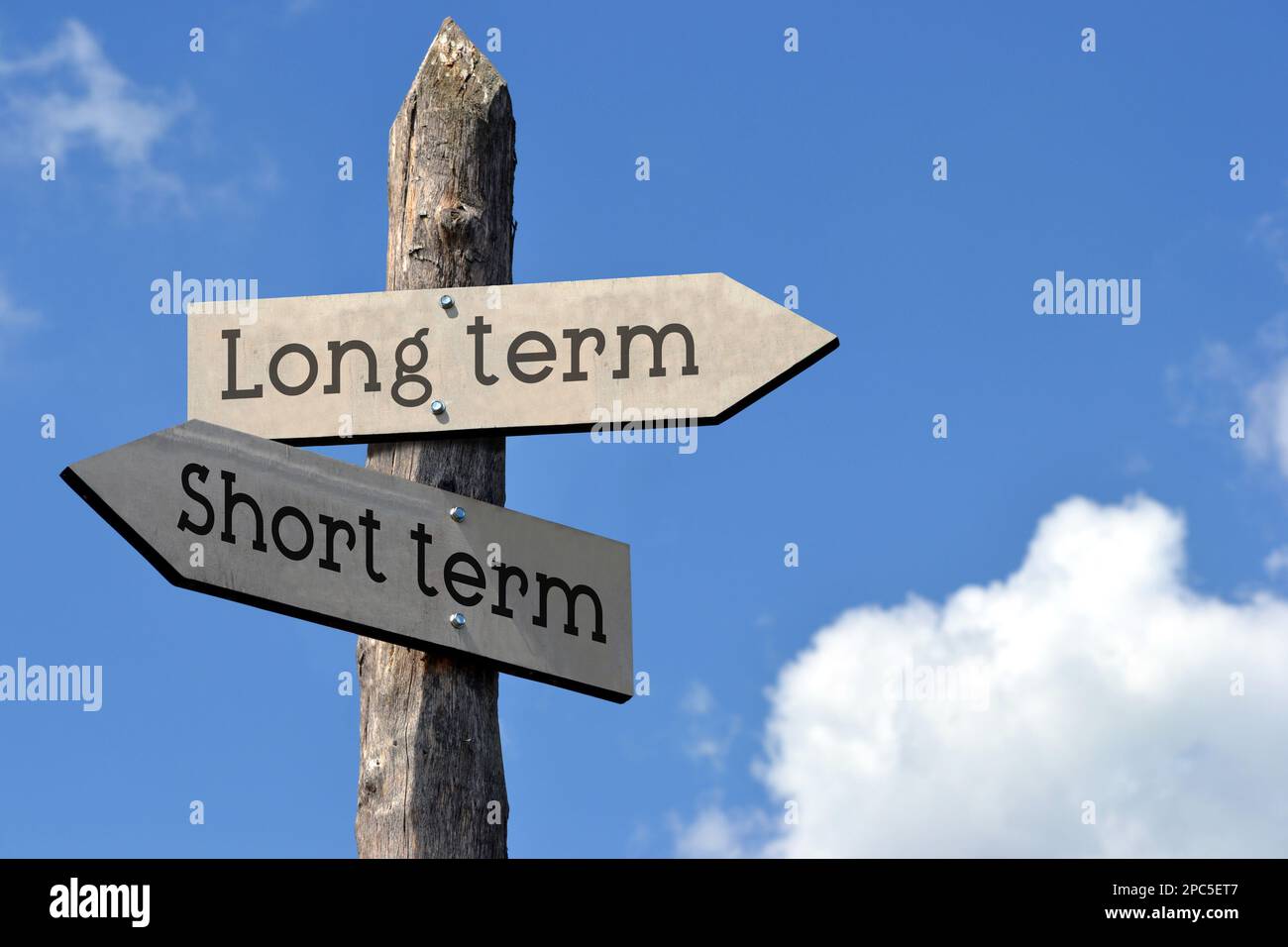 Short or long term - wooden signpost with two arrows, sky with clouds ...