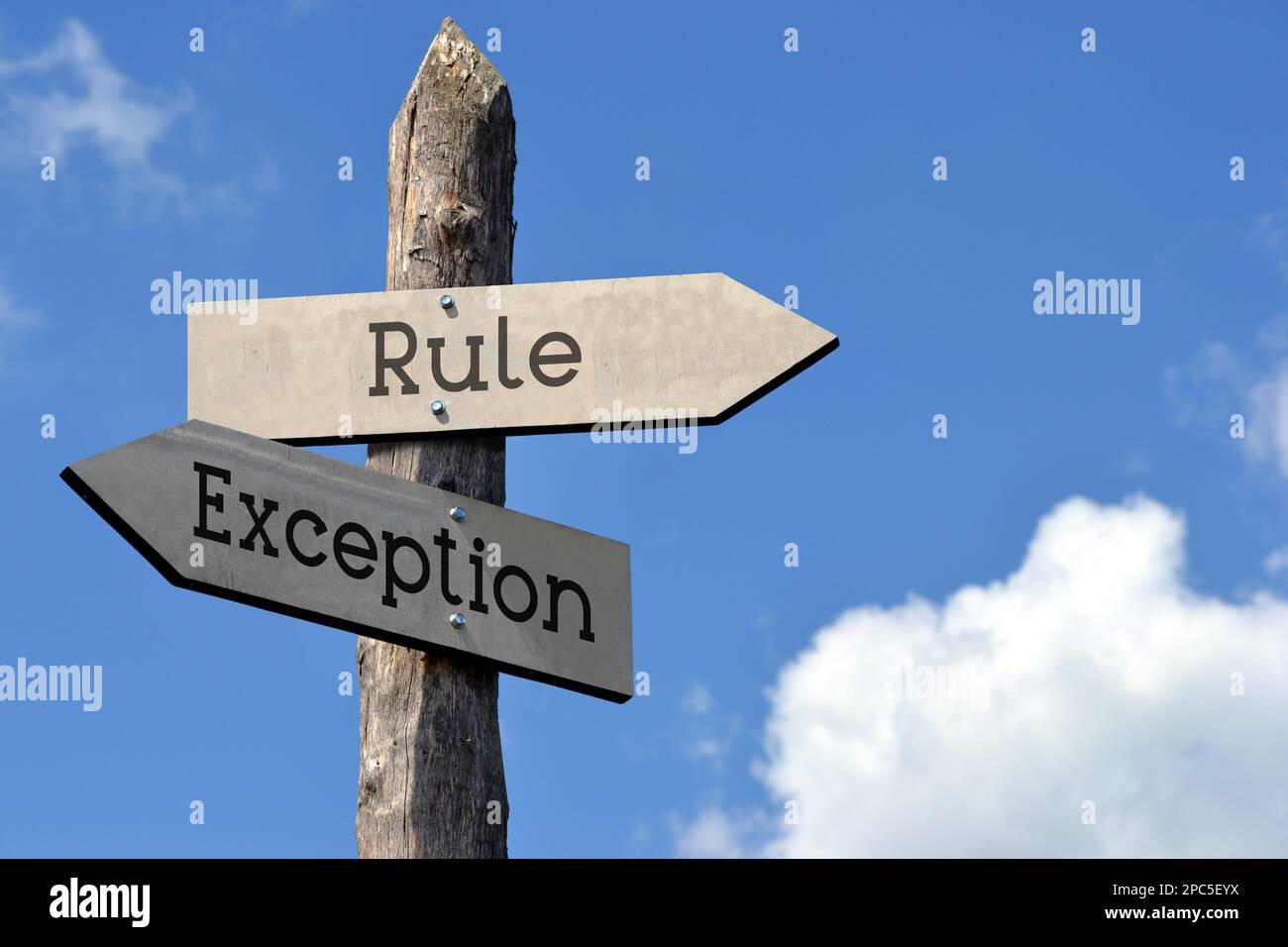 Rule or exception - wooden signpost with two arrows, sky with clouds Stock Photo - Alamy