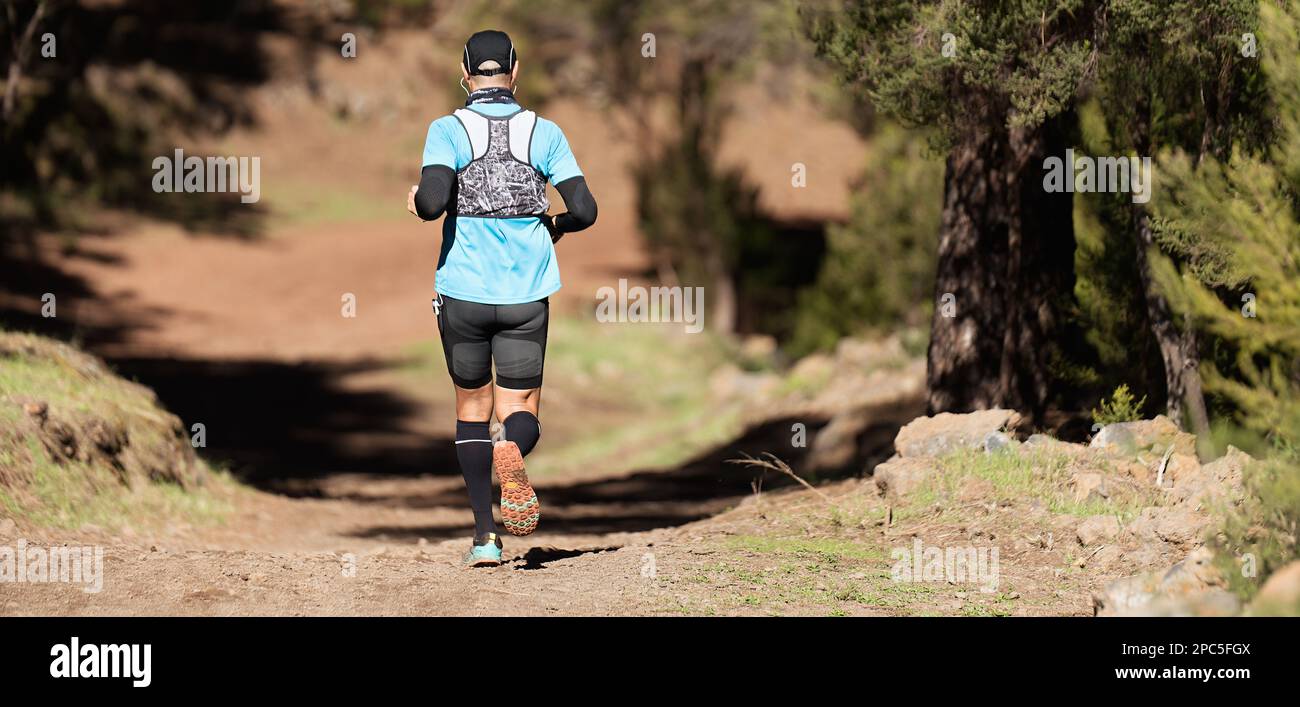 Athlete man running mountain marathon along a forest trail with a ...