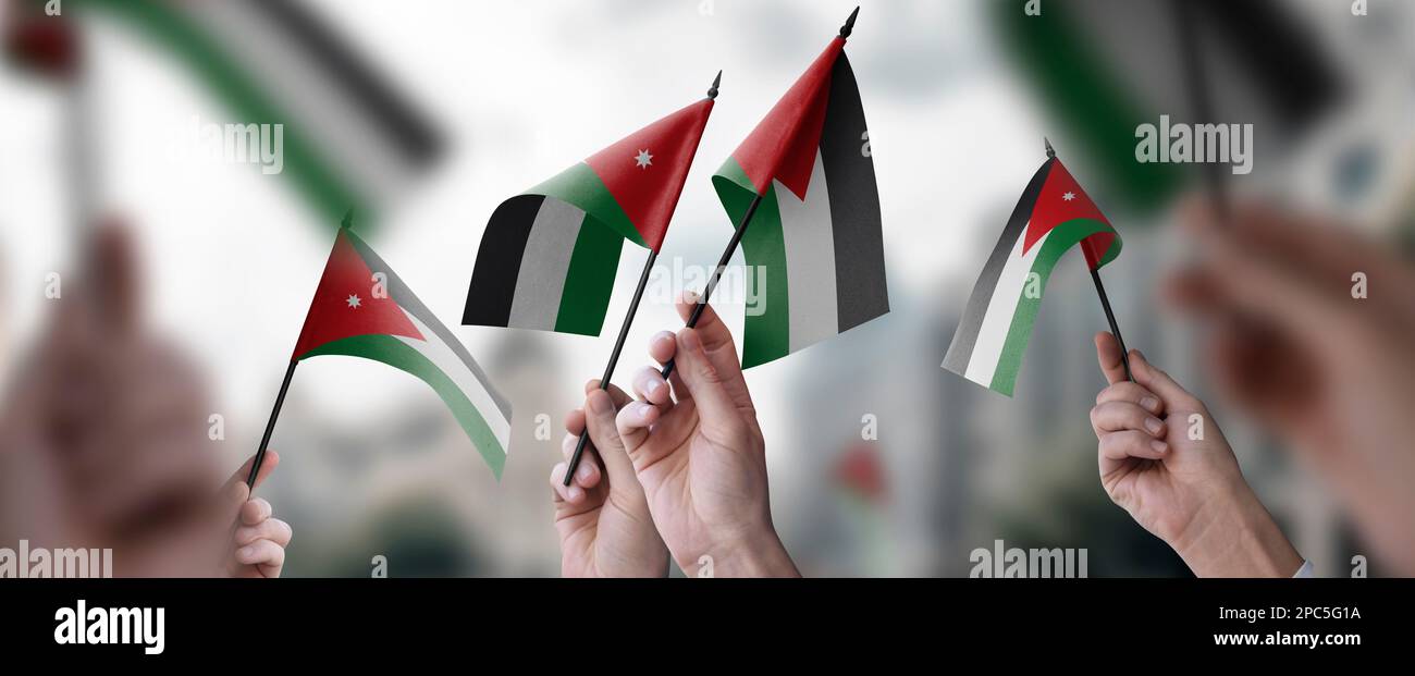 A group of people holding small flags of the Jordan in their hands ...