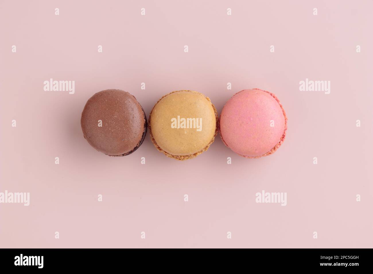 Three pastel colored macaroons on pink background, colorful french ...