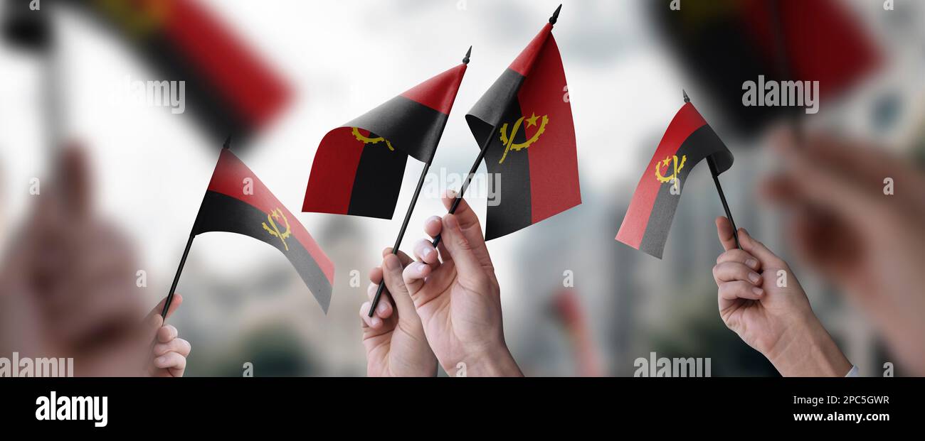 A group of people holding small flags of the Angola in their hands ...