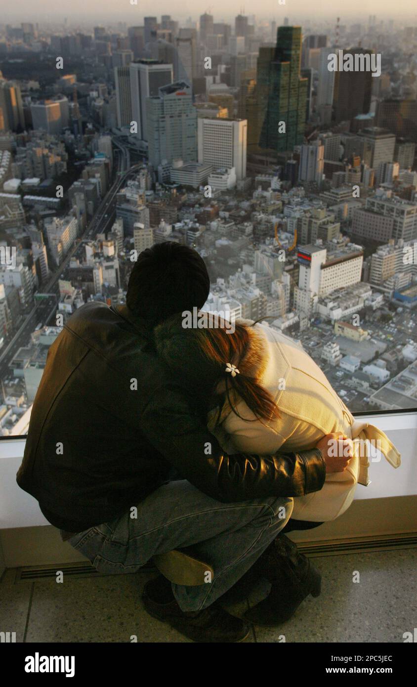 A Japanese couple sit together at a window to watch the first sunrise ...