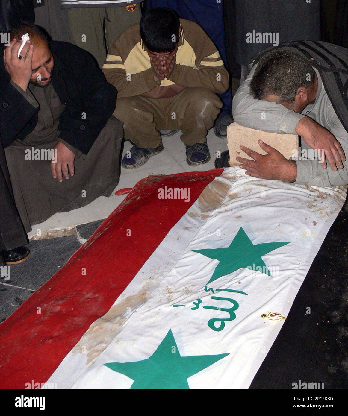 Iraqis grieve beside the burial site of former Iraqi president Saddam ...