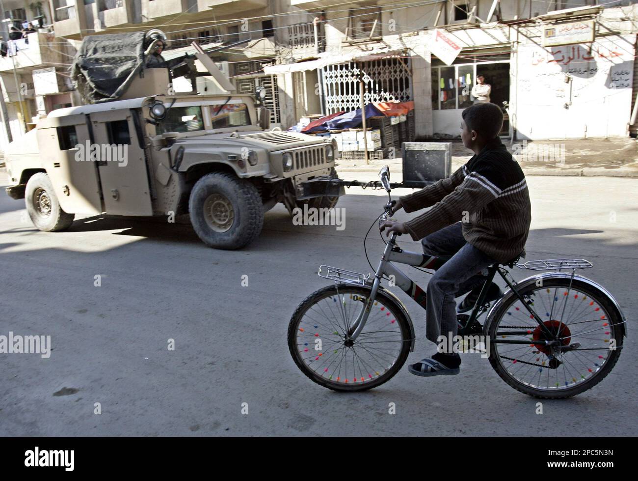 An Iraqi boy rides by a U.S. Humvee as soldiers from the Army's 2nd ...