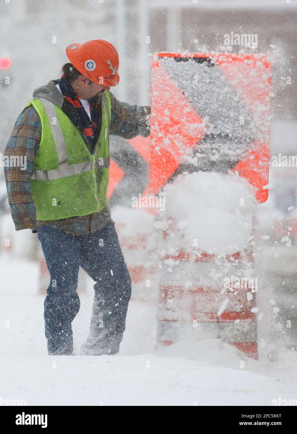 Worker Scott Wilson removes snow from a road construction sign at an ...