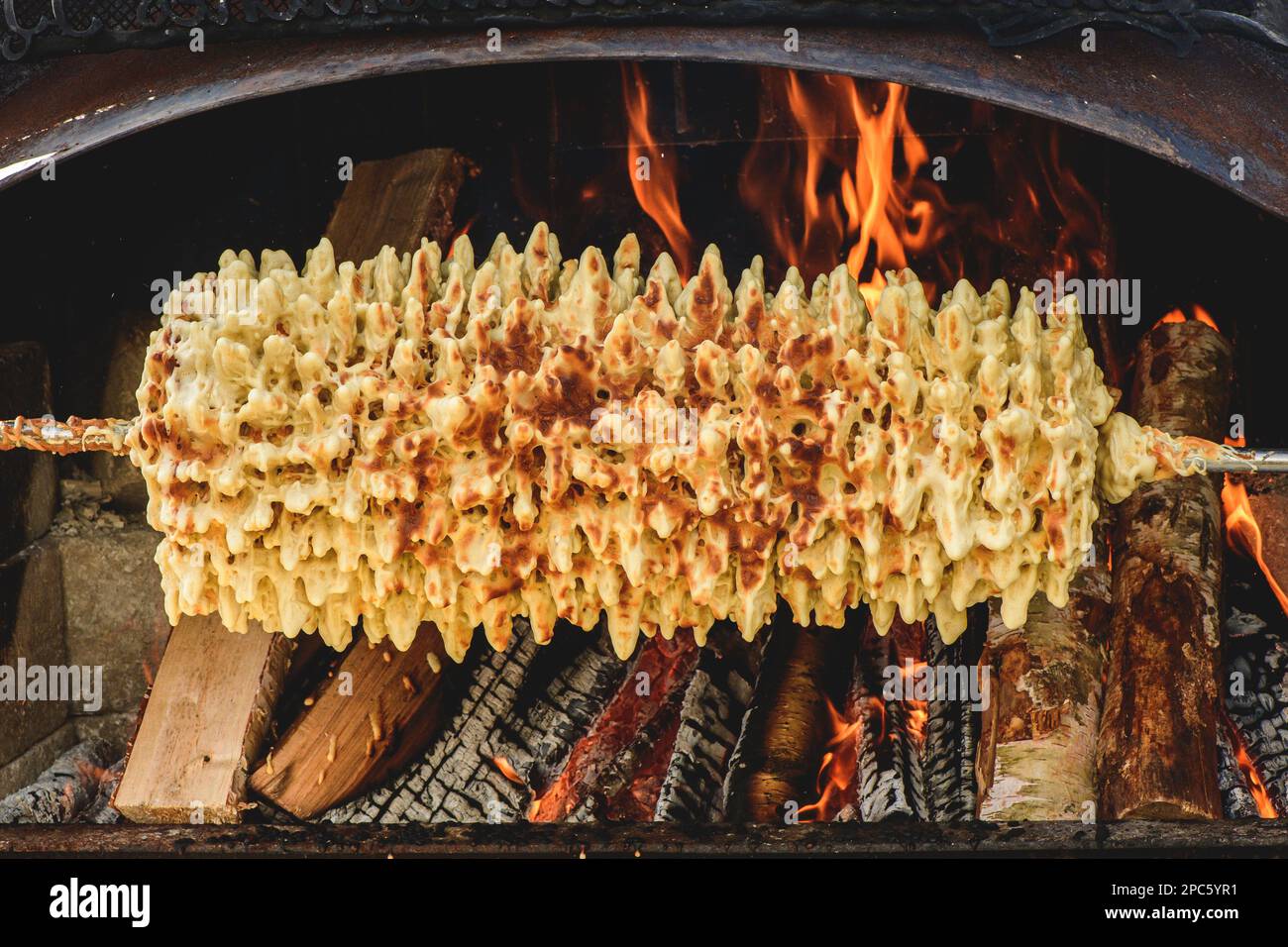 Preparing Lithuanian tree cake, šakotis or baumkuchenas, Polish sękacz ...