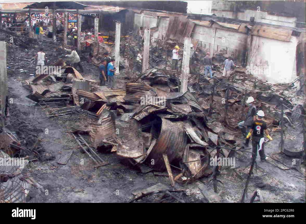 Firemen and rescuers sift through the burnt remains of a one-storey ...