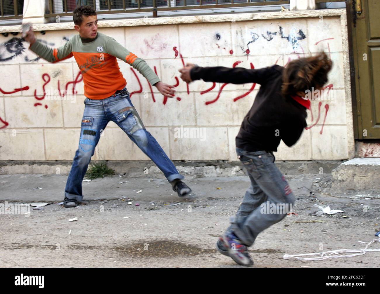 Palestinian youths hurl stones at Israeli troops, not seen, during an ...