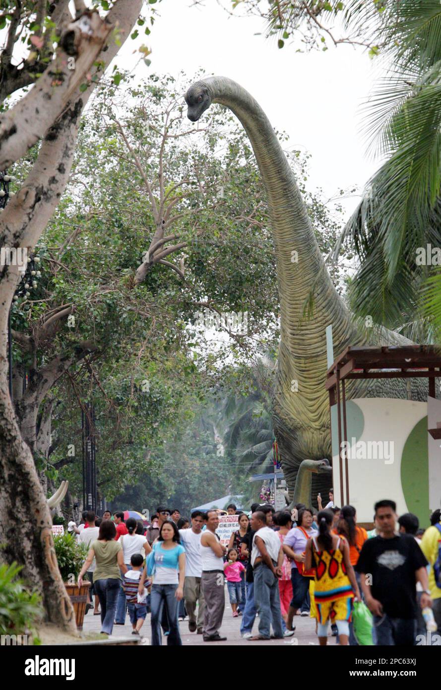 A life-size replica of a Brontosaurus towers above park goers on ...
