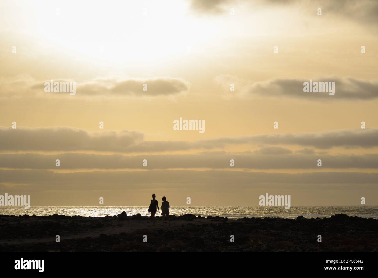 Silhouette at sunset of some walkers on the beach in Fuerteventura ...