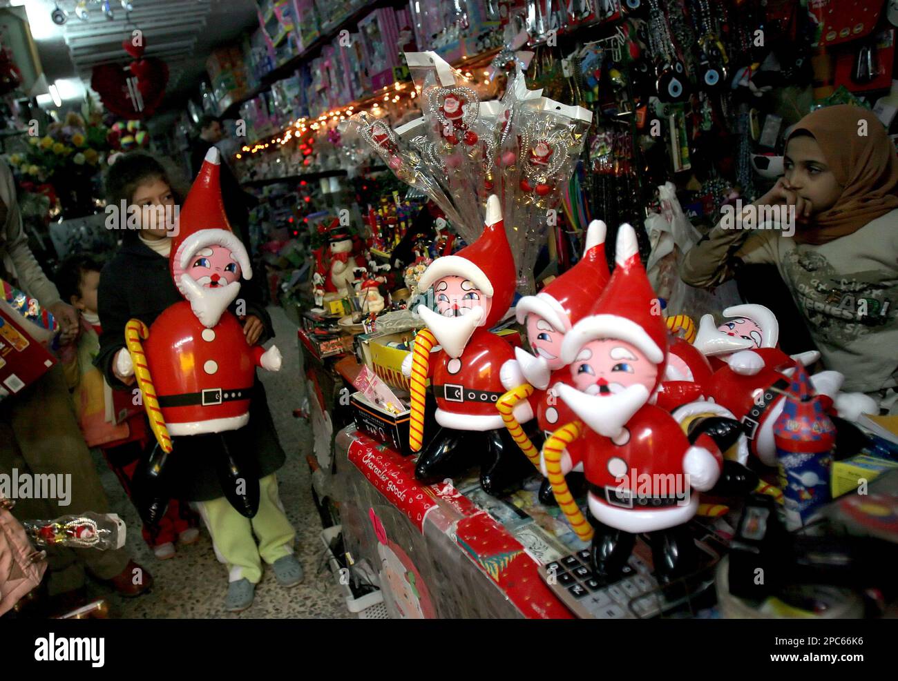 An Iraqi girl carries an inflatable Santa doll in a shop in Baghdad ...
