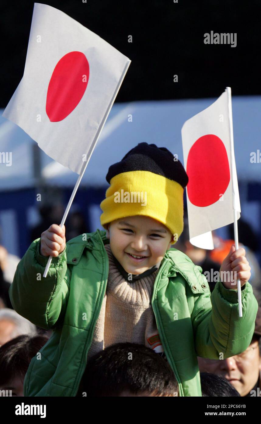 A boy riding on an adult's shoulders waves Japanese flags when Japan's ...