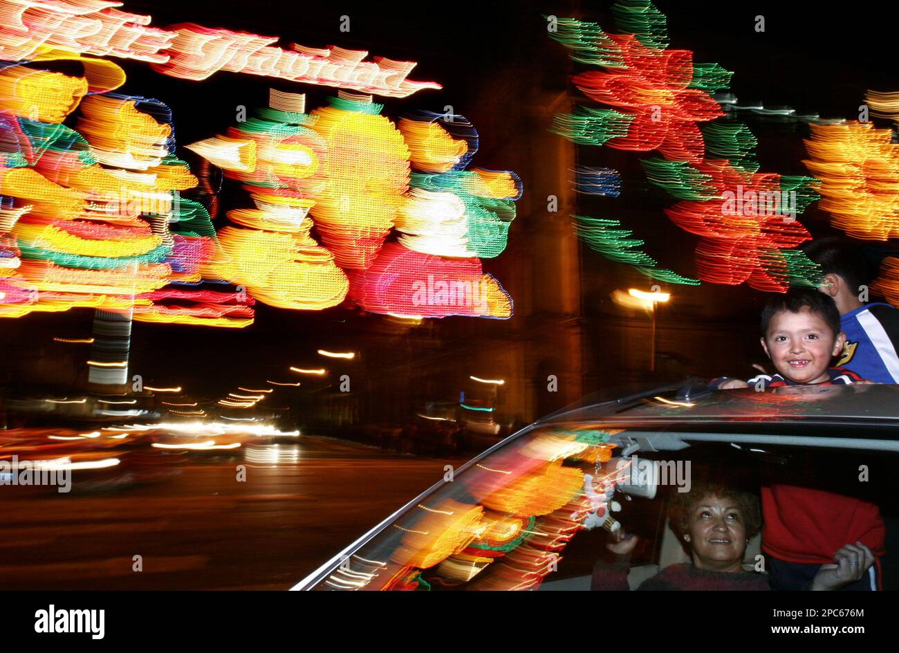A family drives beneath bright Christmas lights in the central plaza of ...