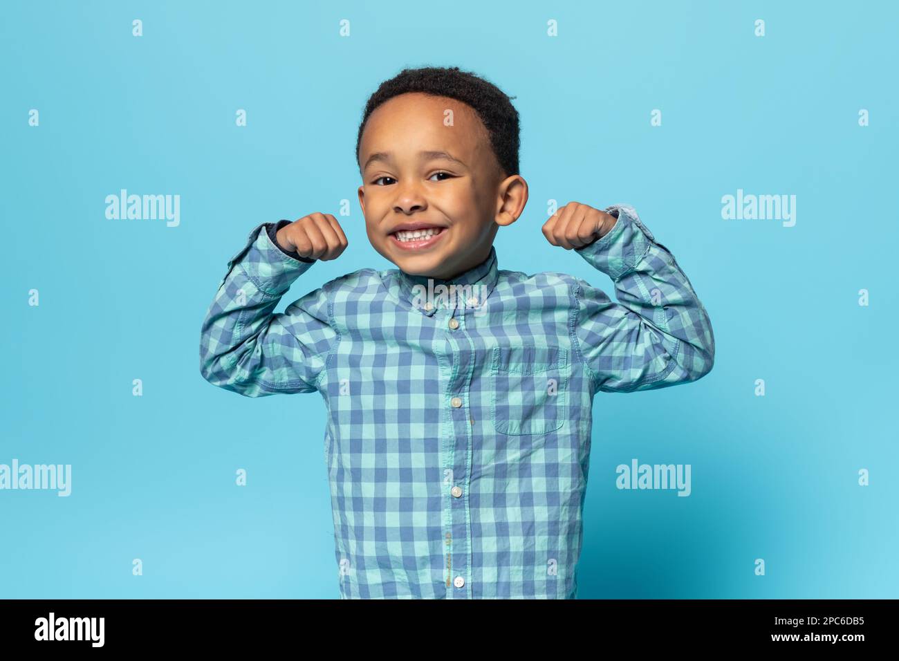 Funny black boy showing biceps and smiling at camera, african american ...