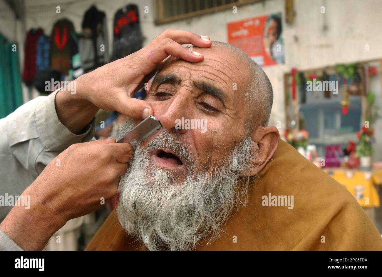 An Afghan street- barber, not seen, shaves the mustache part of an ...