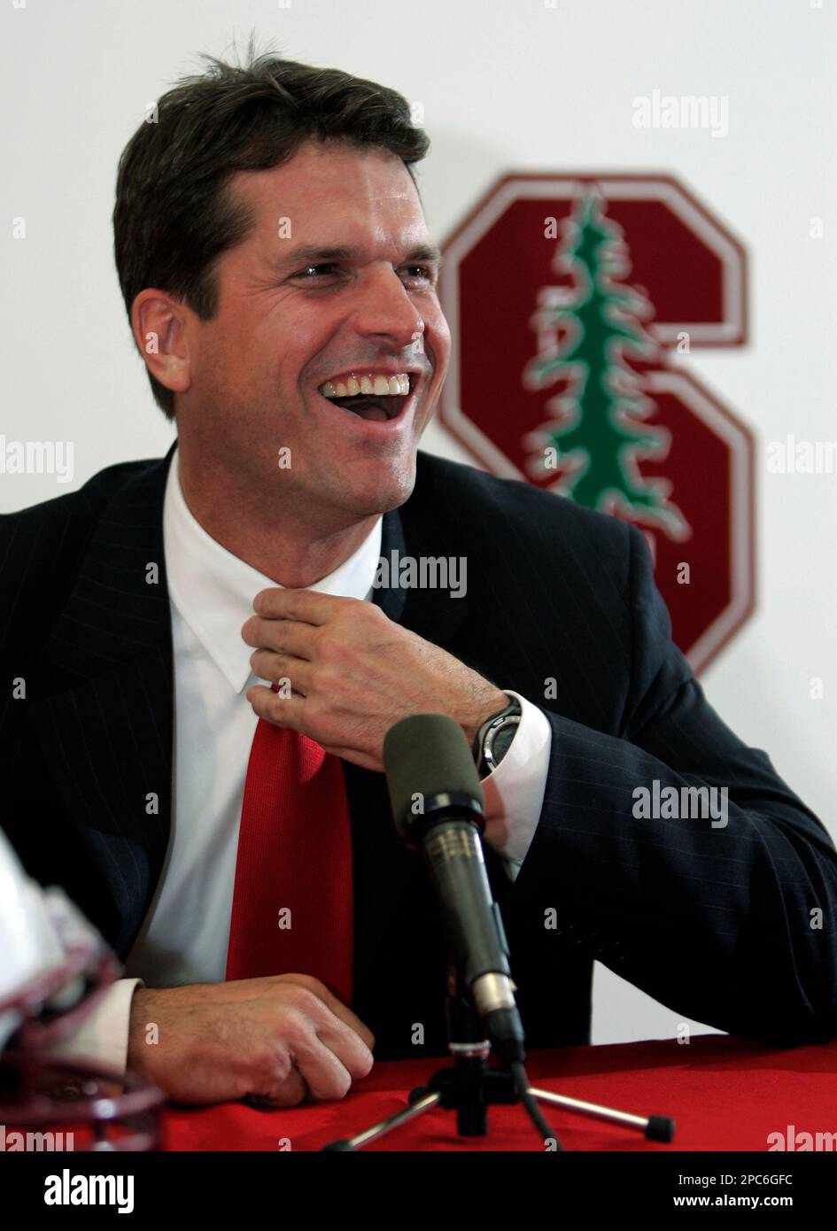 New Stanford head football coach Jim Harbaugh smiles during a news ...