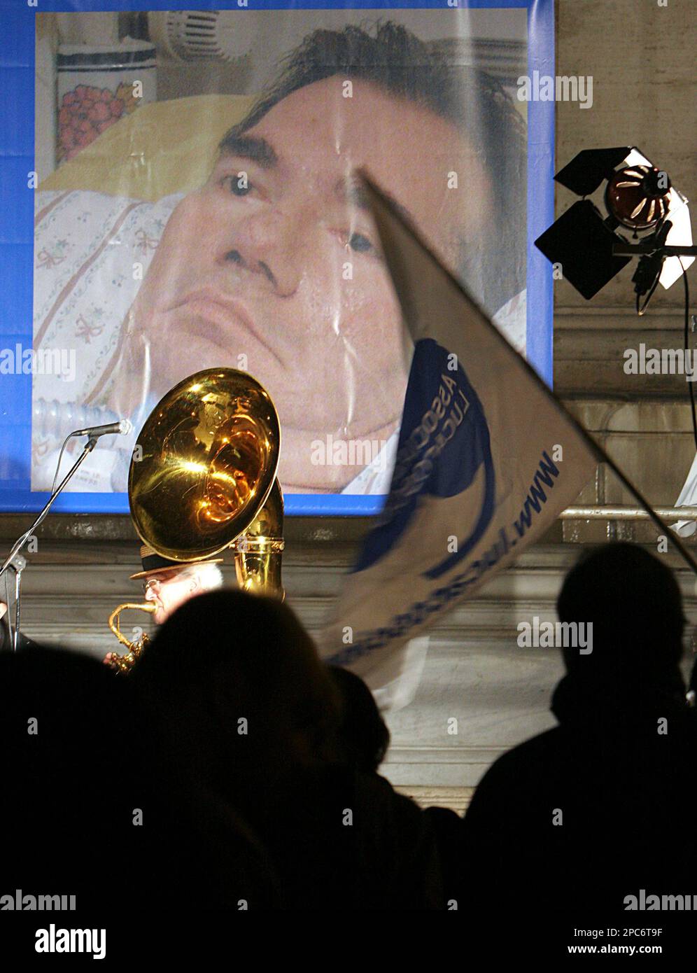 Demonstrators gather in front of a banner bearing the picture of ...
