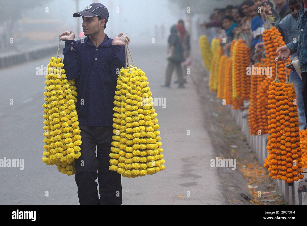 Merrygold garland vendors await the bus in the morning fog in Gauhati ...
