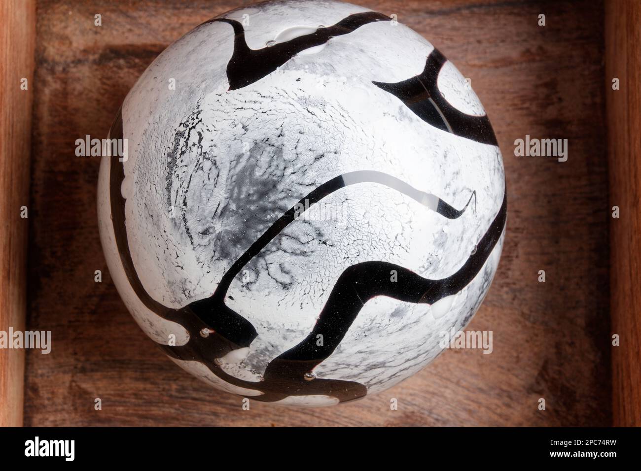 structured black and white glass sphere inside a wooden box isolated on ...
