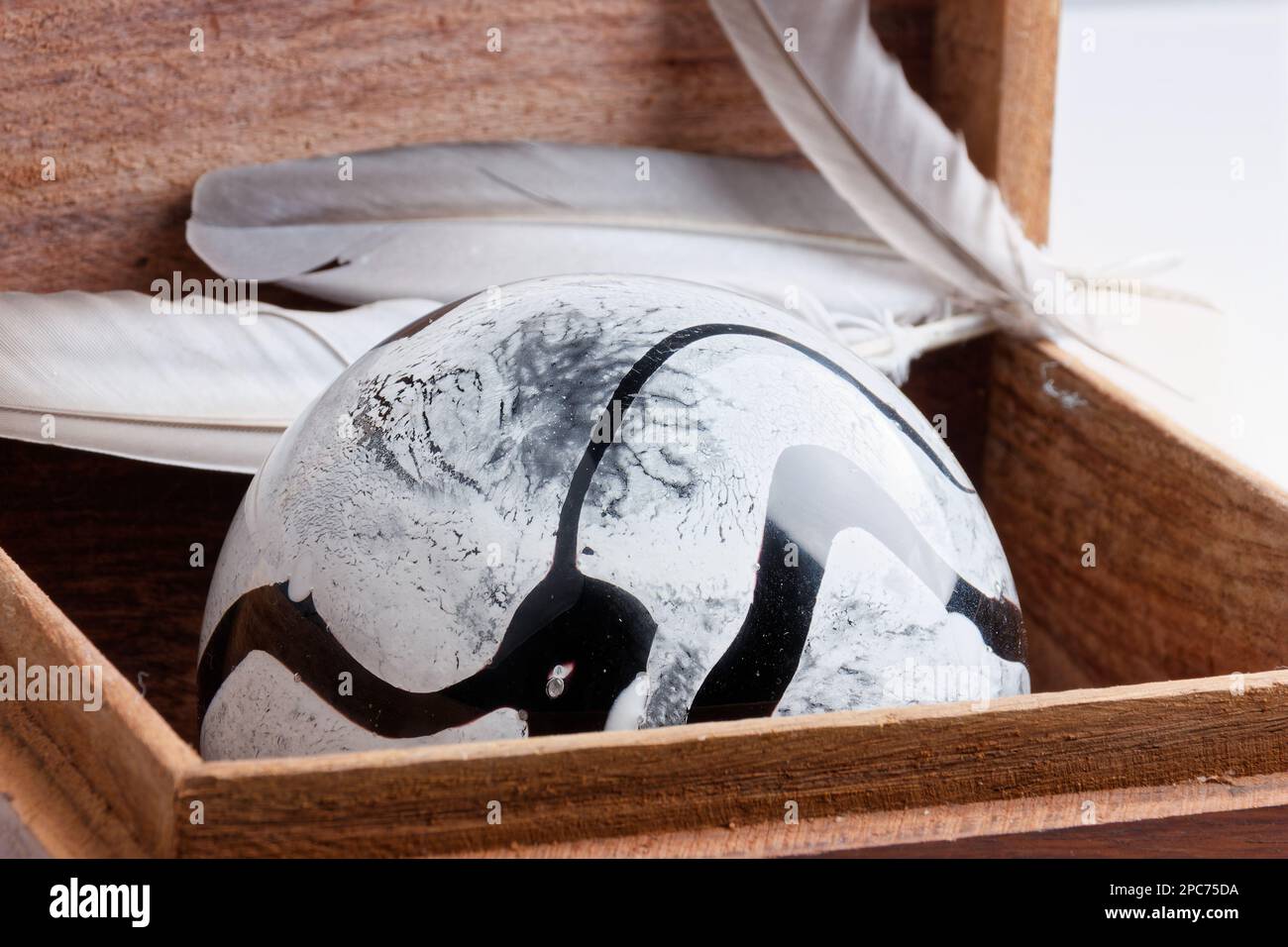 structured black and white glass sphere inside a wooden box isolated on ...