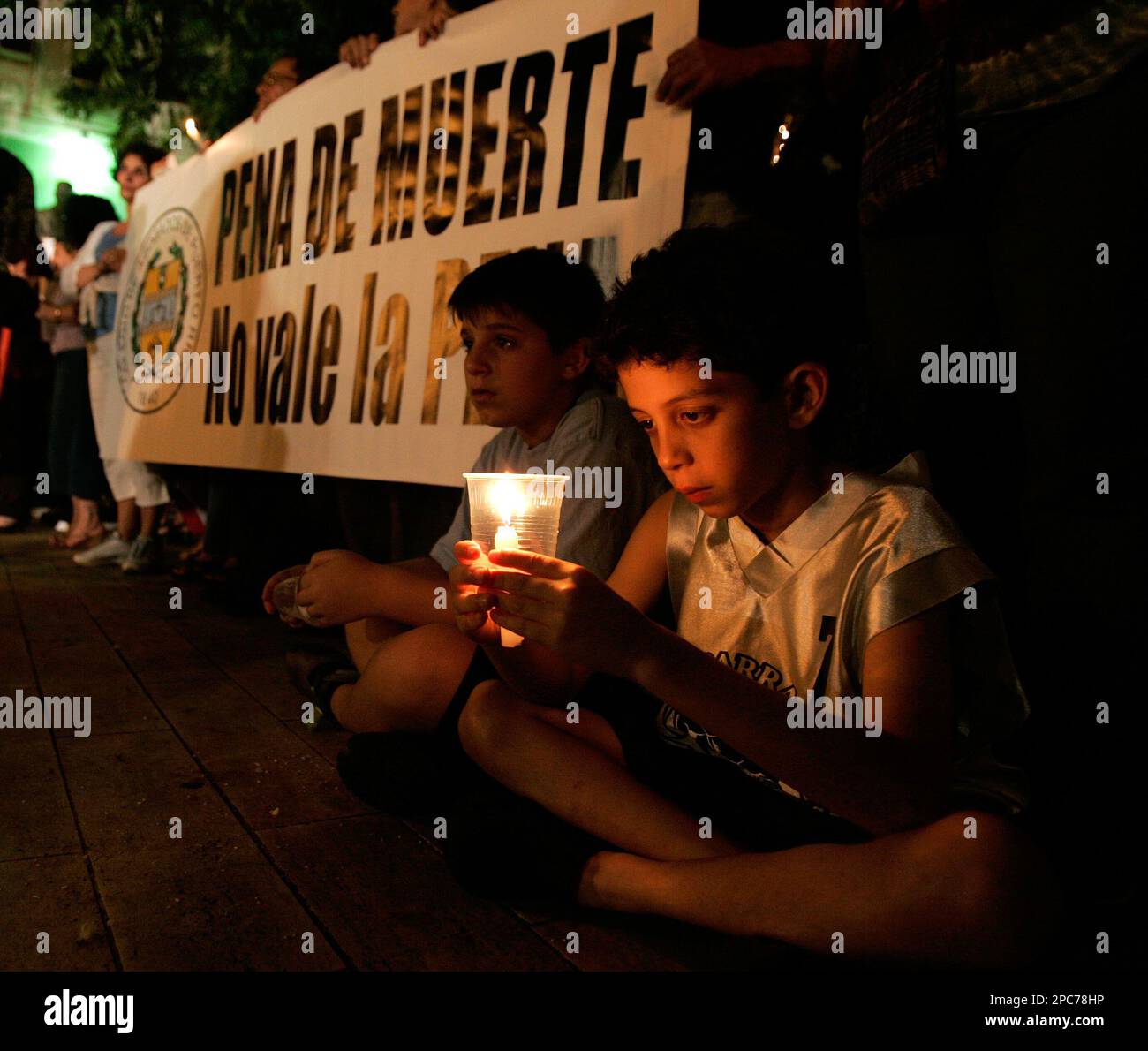 Sebastian Otero, right, and Marcos Jimenez hold candles in front of a ...