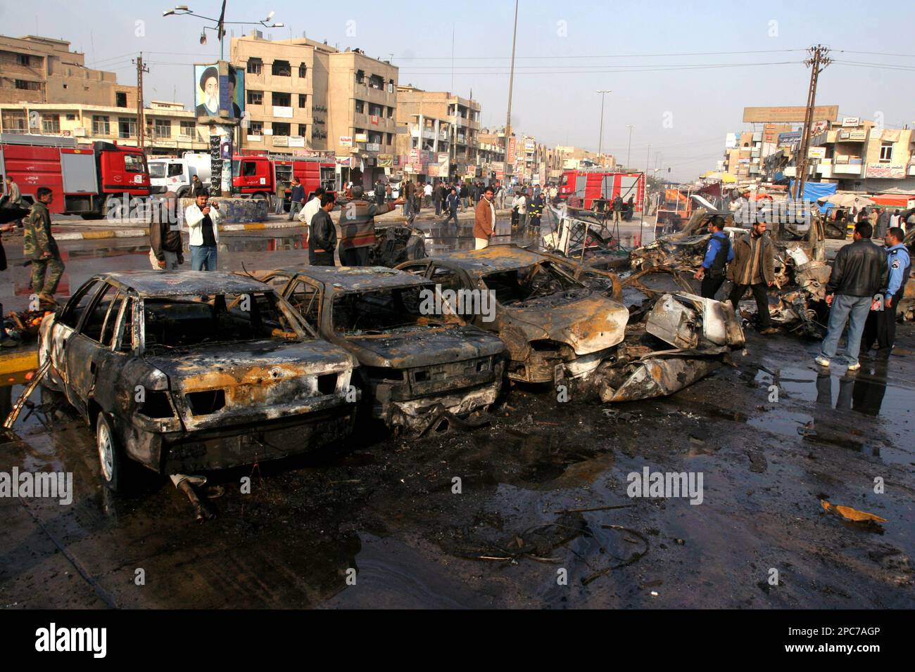 Iraqis look at cars destroyed in a car bomb explosion in the New ...