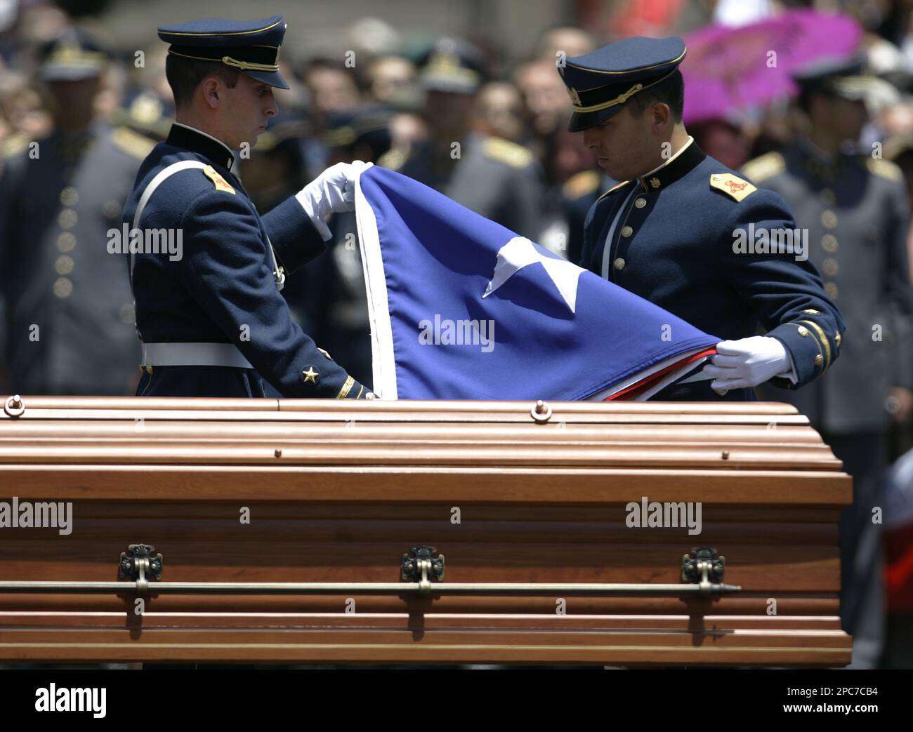 Two soldiers fold the flag that covered the casket with the remains of ...