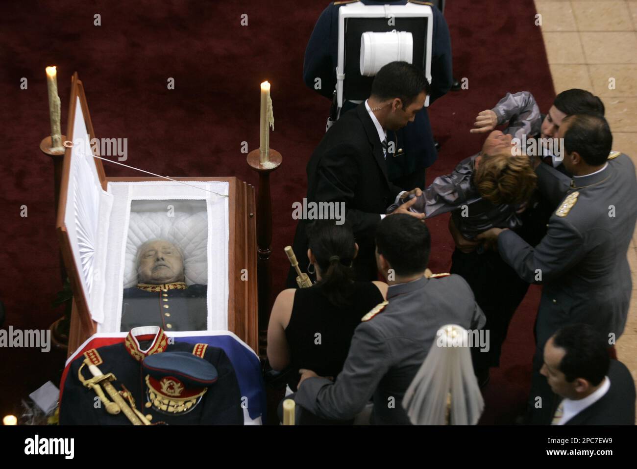 A supporter of former military ruler Gen. Augusto Pinochet is helped as ...
