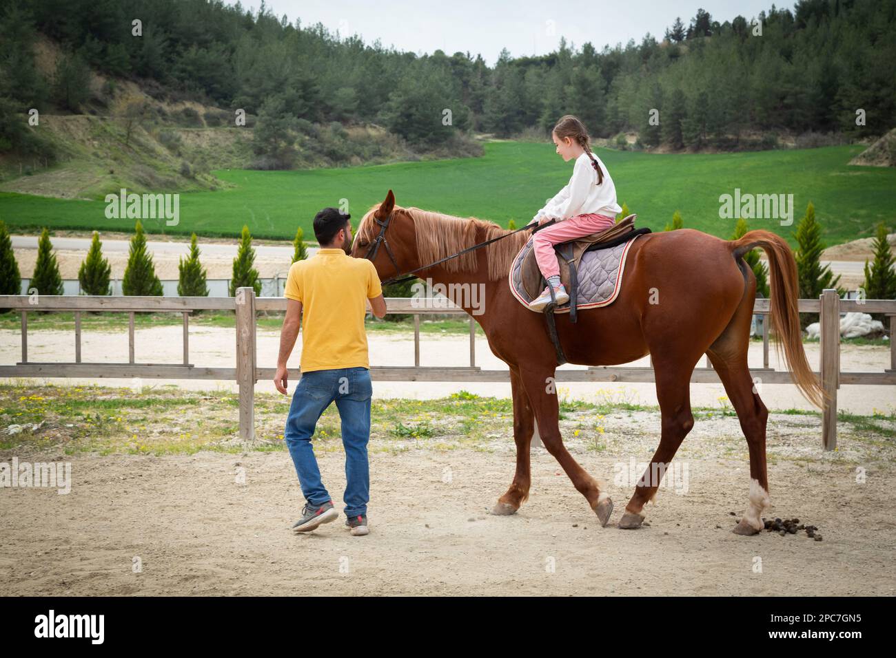Happy little girl taking a ride on horseback at riding school. Girl ...